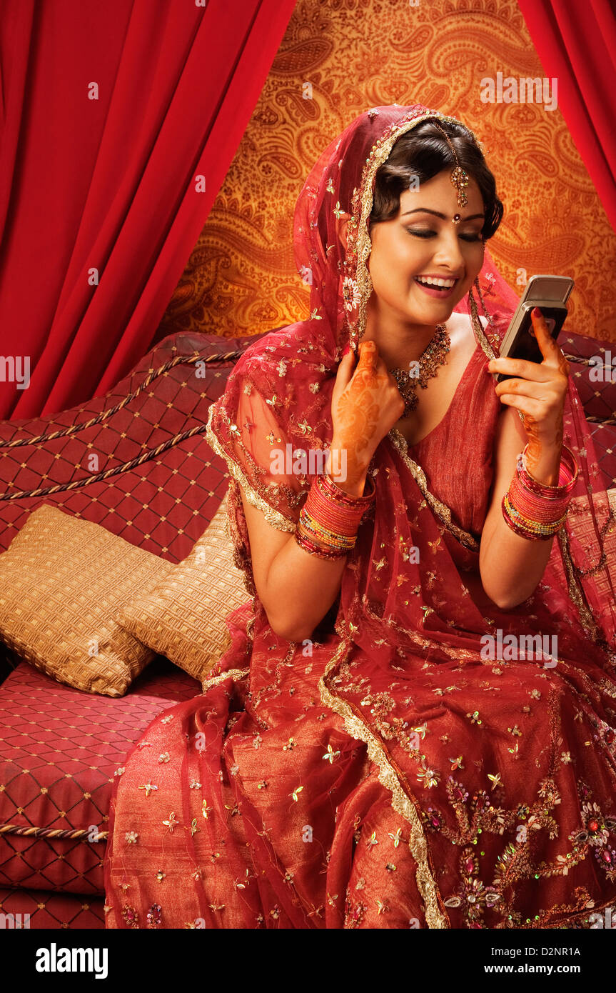 Bride in traditional wedding dress and using a mobile phone Stock Photo - Alamy