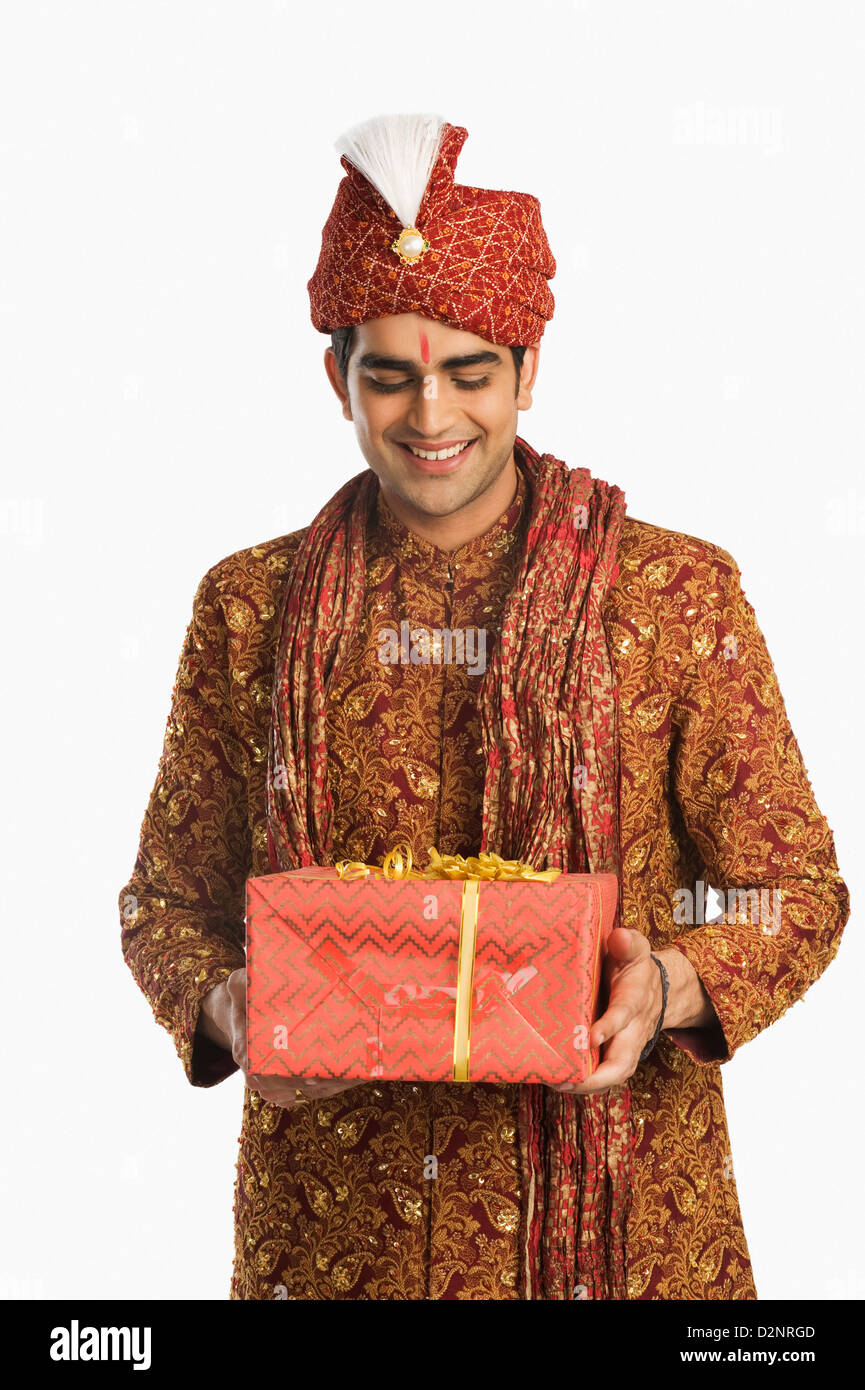 Groom in traditional wedding outfit holding a gift Stock Photo - Alamy