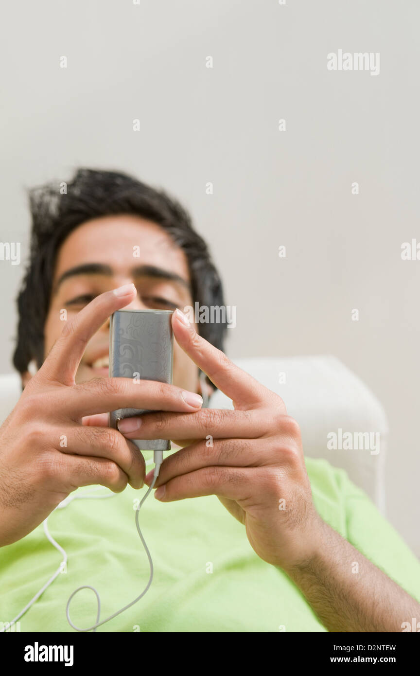 Man listening to an MP3 player on a couch Stock Photo - Alamy