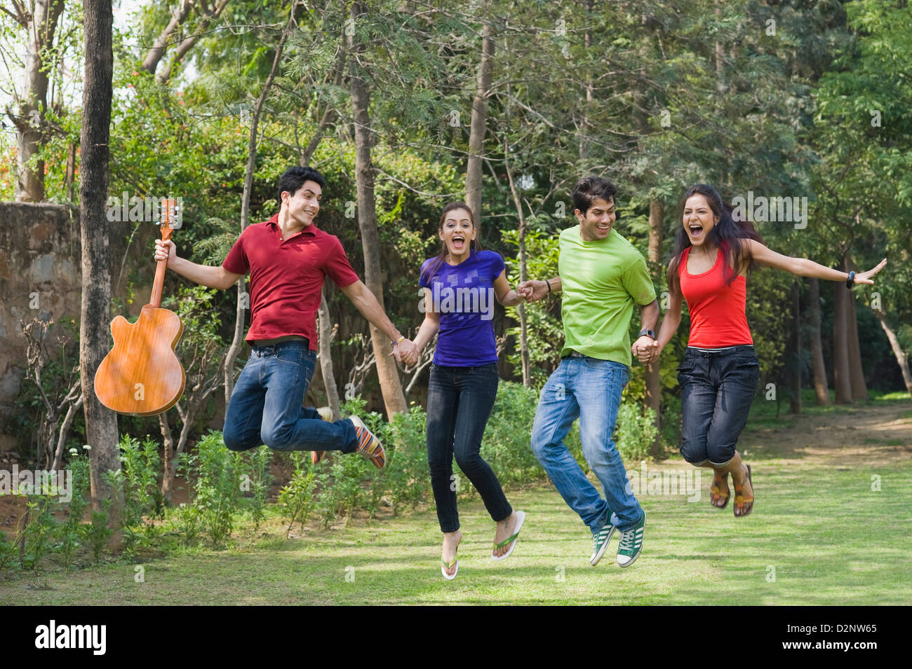 Four friends jumping on grass Stock Photo - Alamy
