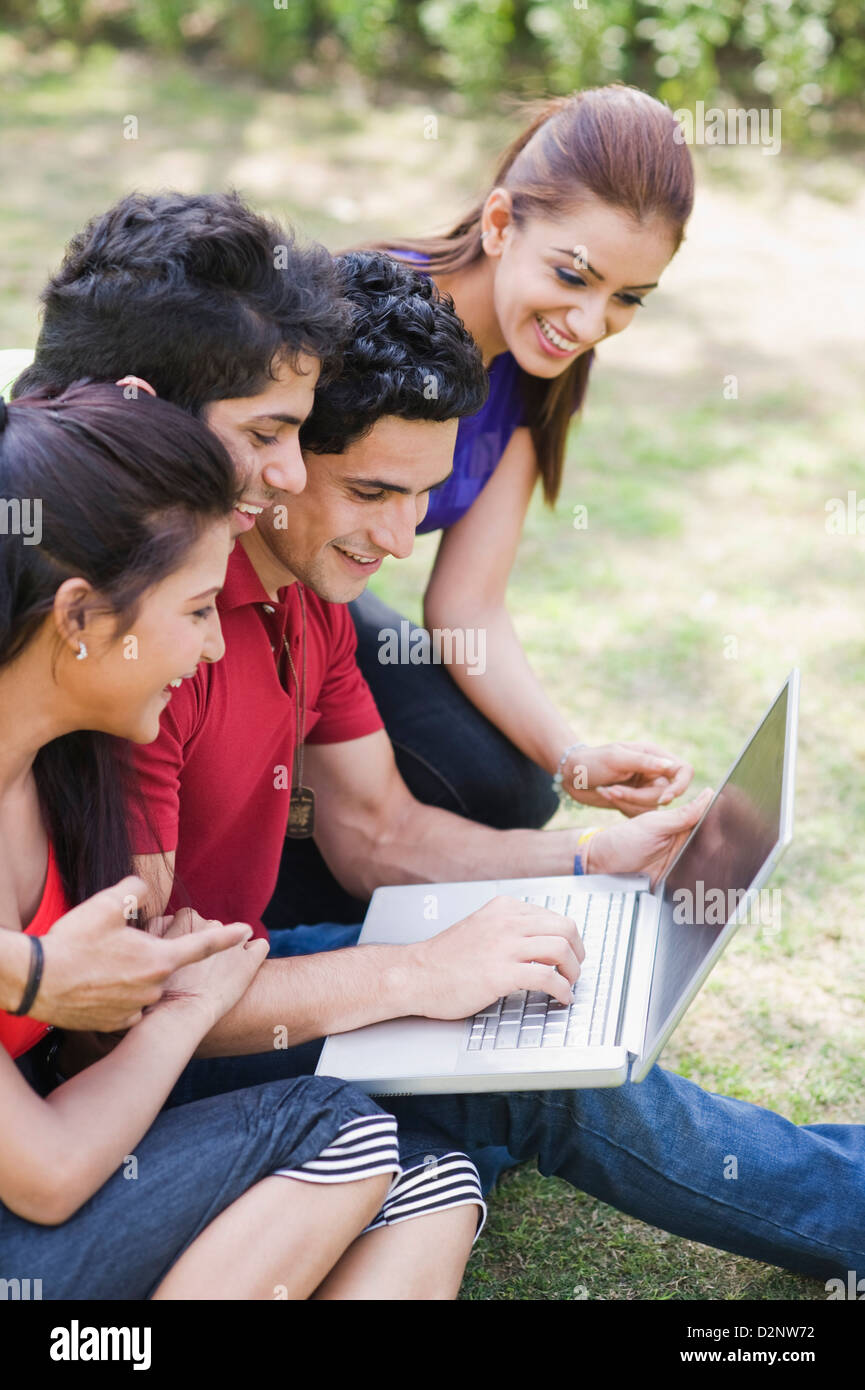 Four friends using a laptop and smiling Stock Photo - Alamy