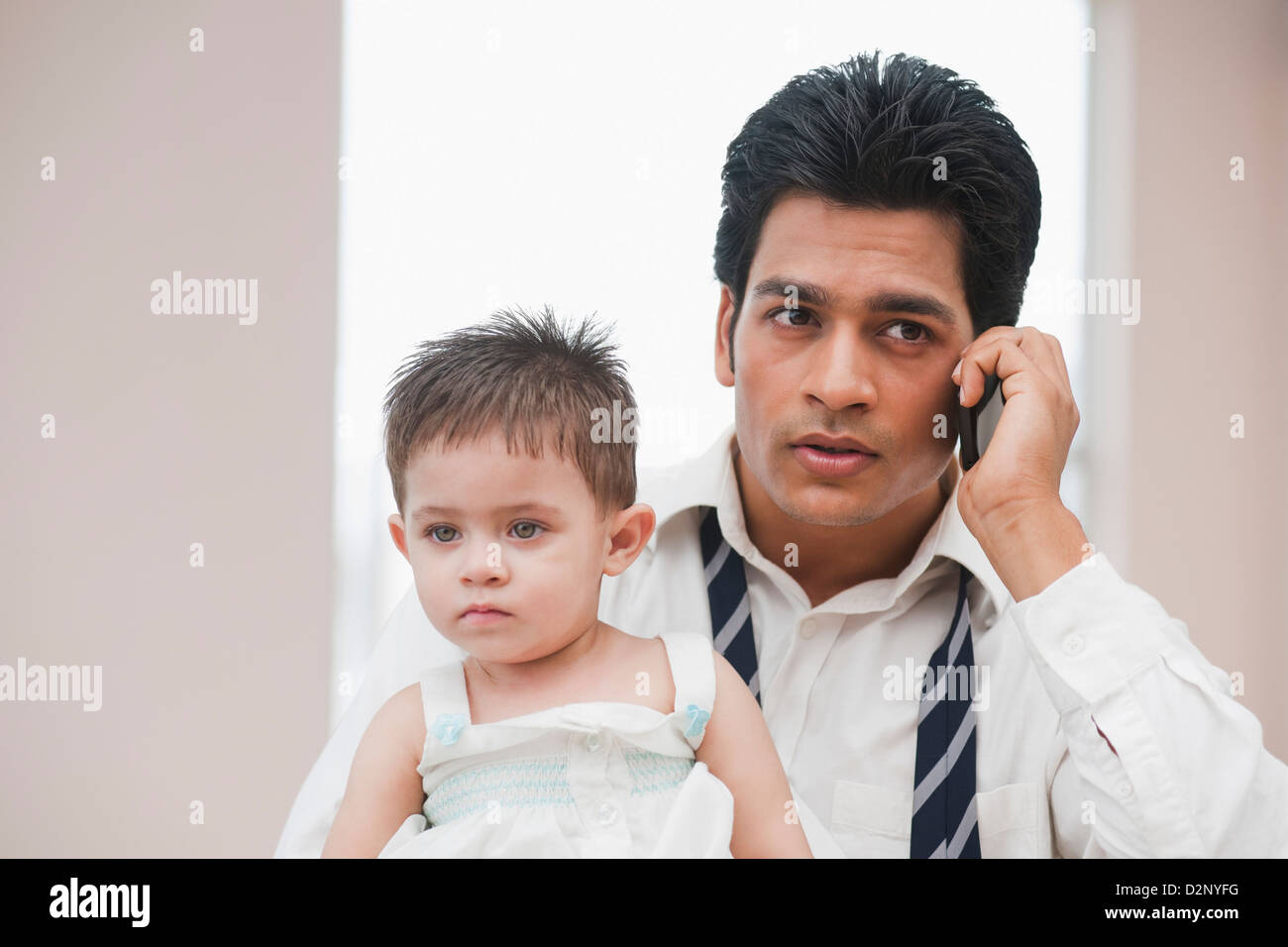 Man talking on a mobile phone and carrying his daughter Stock Photo - Alamy