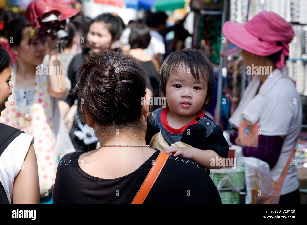 A child being held by a woman looks directly into the camera at Sampeng ...