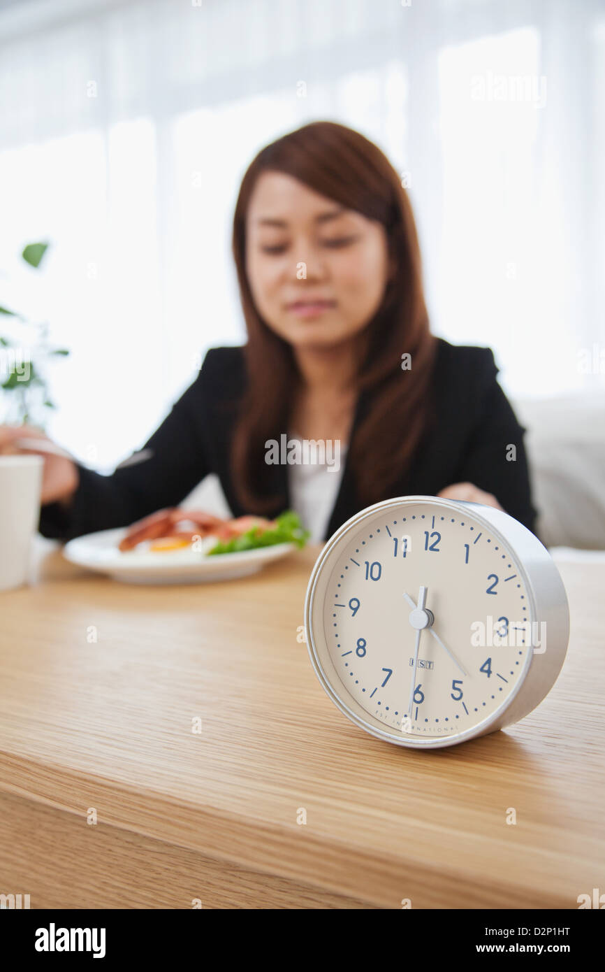 Young woman eating breakfast and alarm clock Stock Photo - Alamy