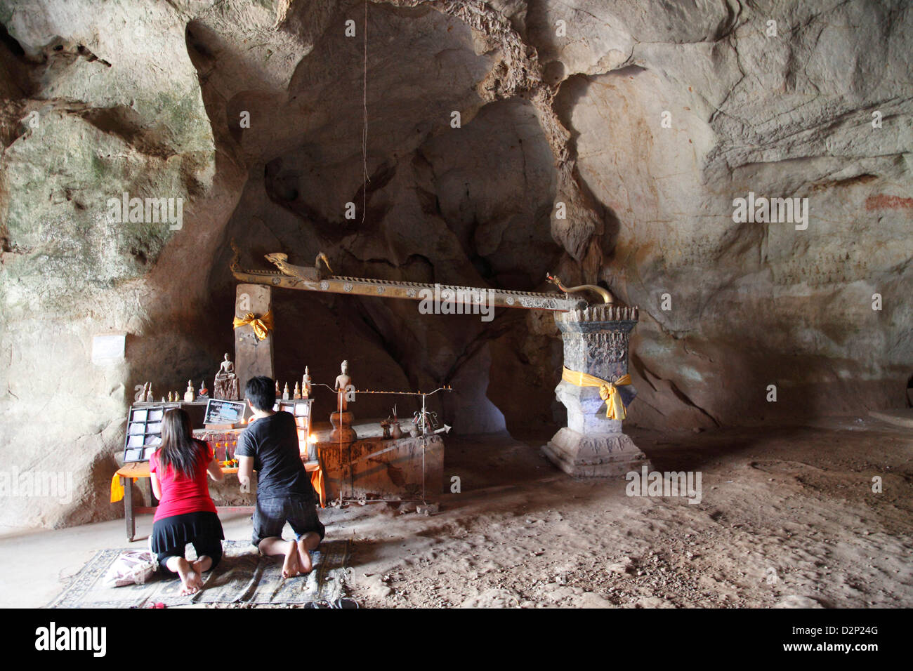 Two people kneeling and praying at a shrine inside the Tham Ting cave ...