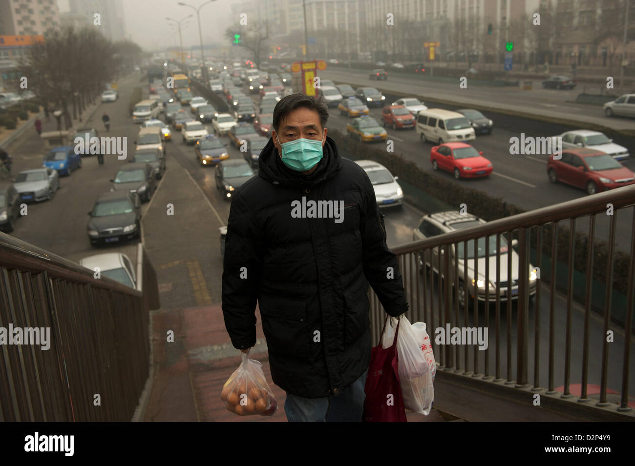 A man wears a mask past heavy traffic in thick haze in Beijing, China ...