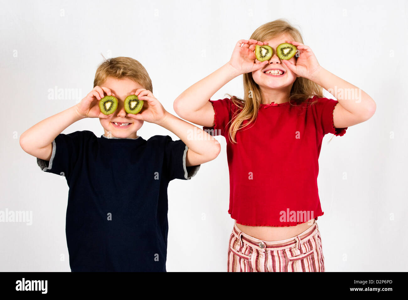 Young children holding kiwi fruit slices over their eyes smiling Stock ...
