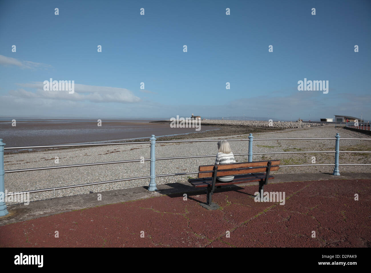 Woman sat on seat looking at sea view Stock Photo - Alamy