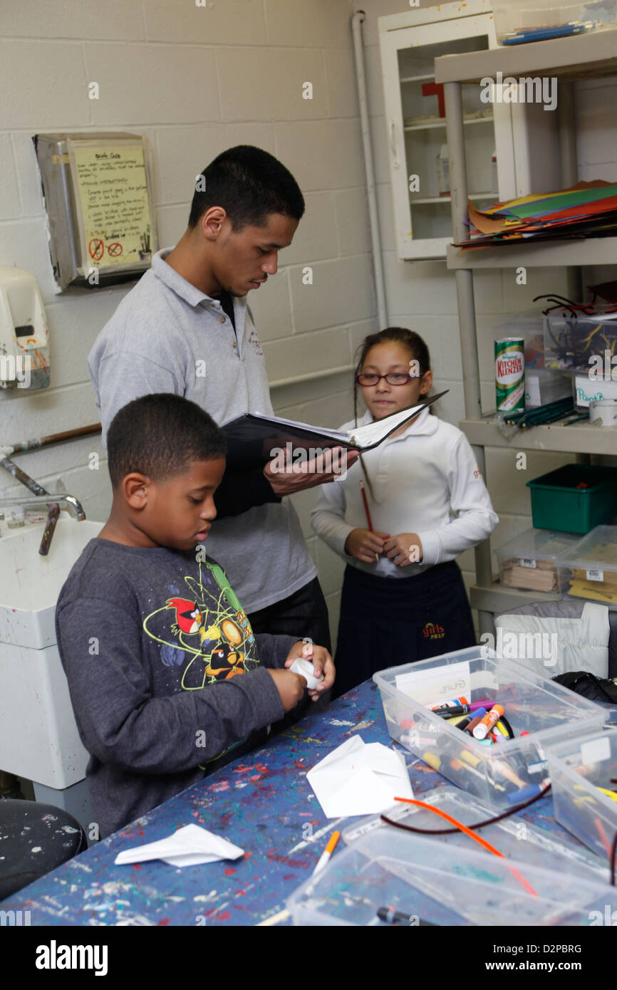 High school age boy works with younger children in an educational after ...