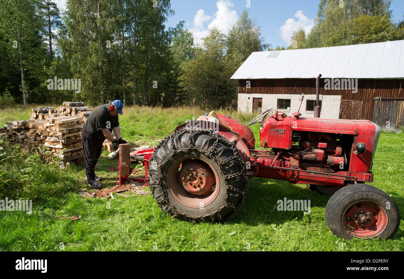 Elderly man making firewood with tractor powered screw log splitter ...