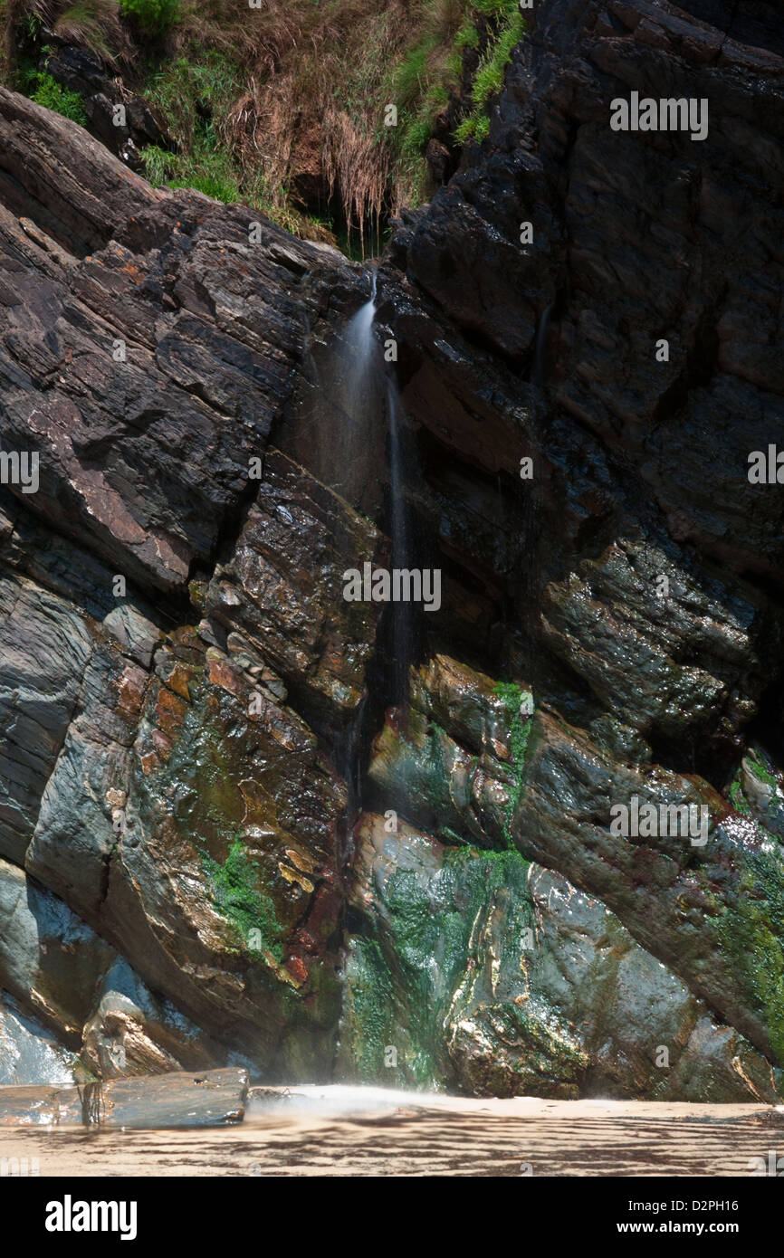 Cliff formation with a small waterfall, on the edge of a beach Stock ...