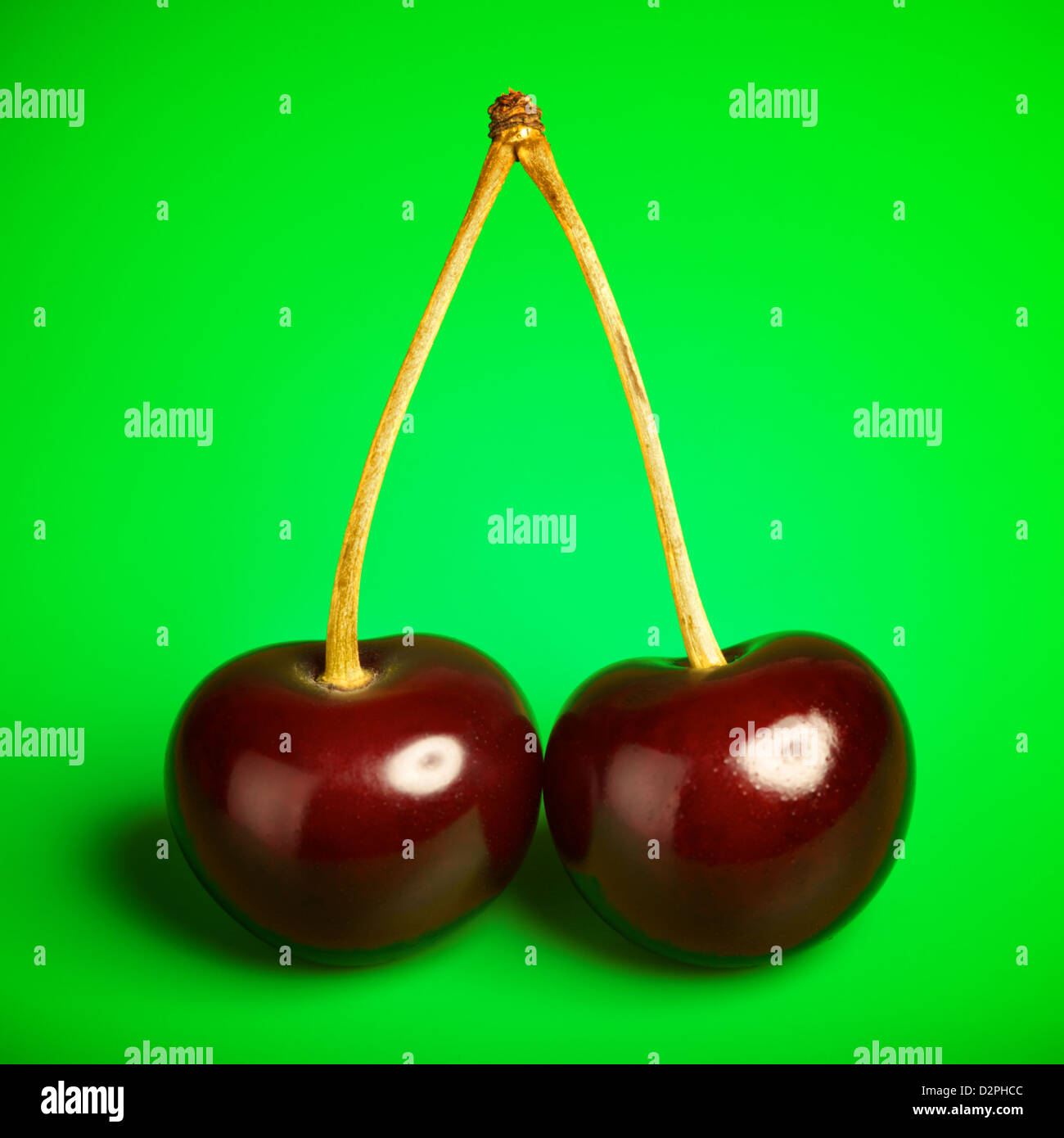 fresh red cherries with stem on green background Stock Photo - Alamy