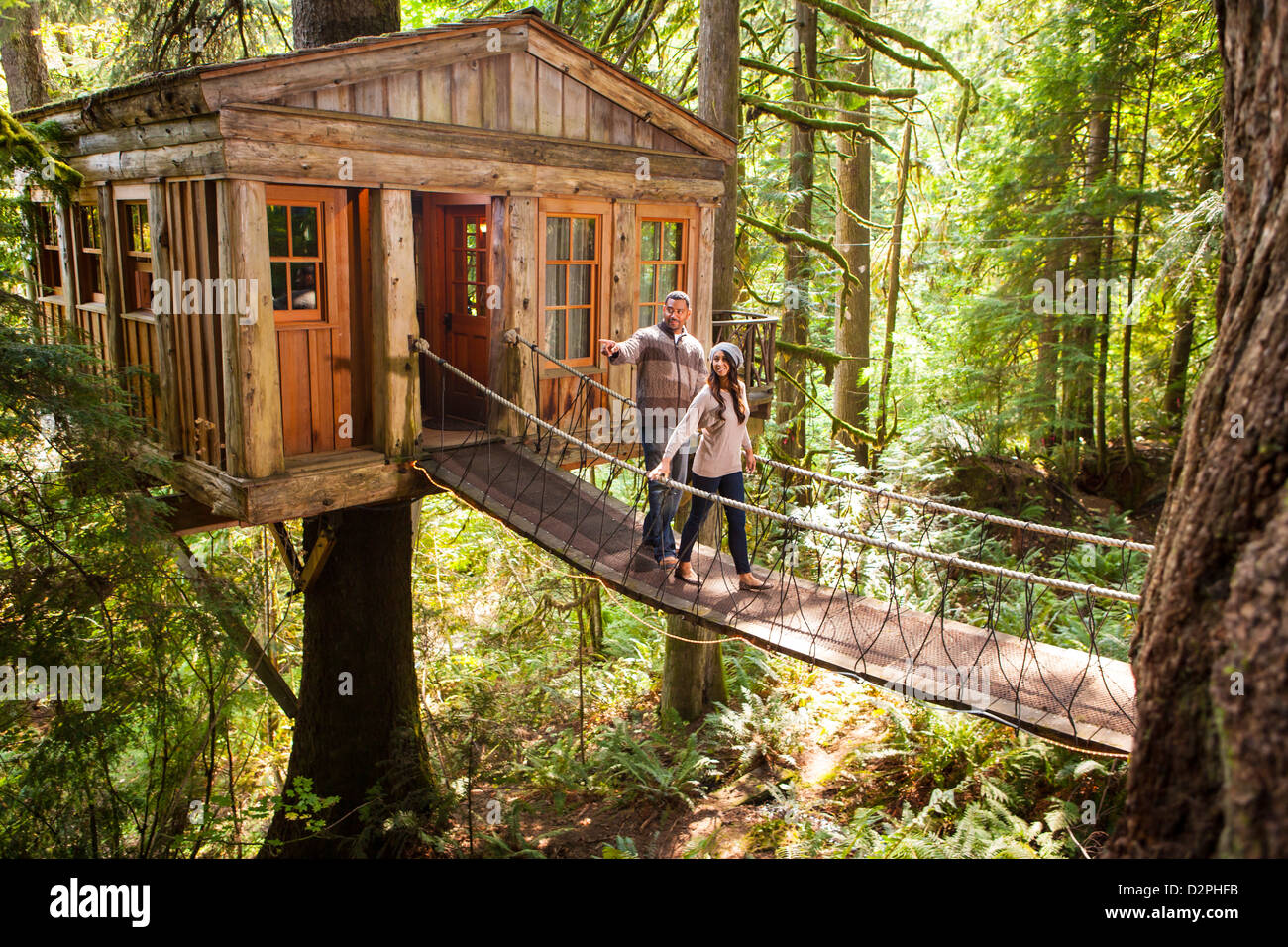 Couple on walkway of remote tree house Stock Photo - Alamy