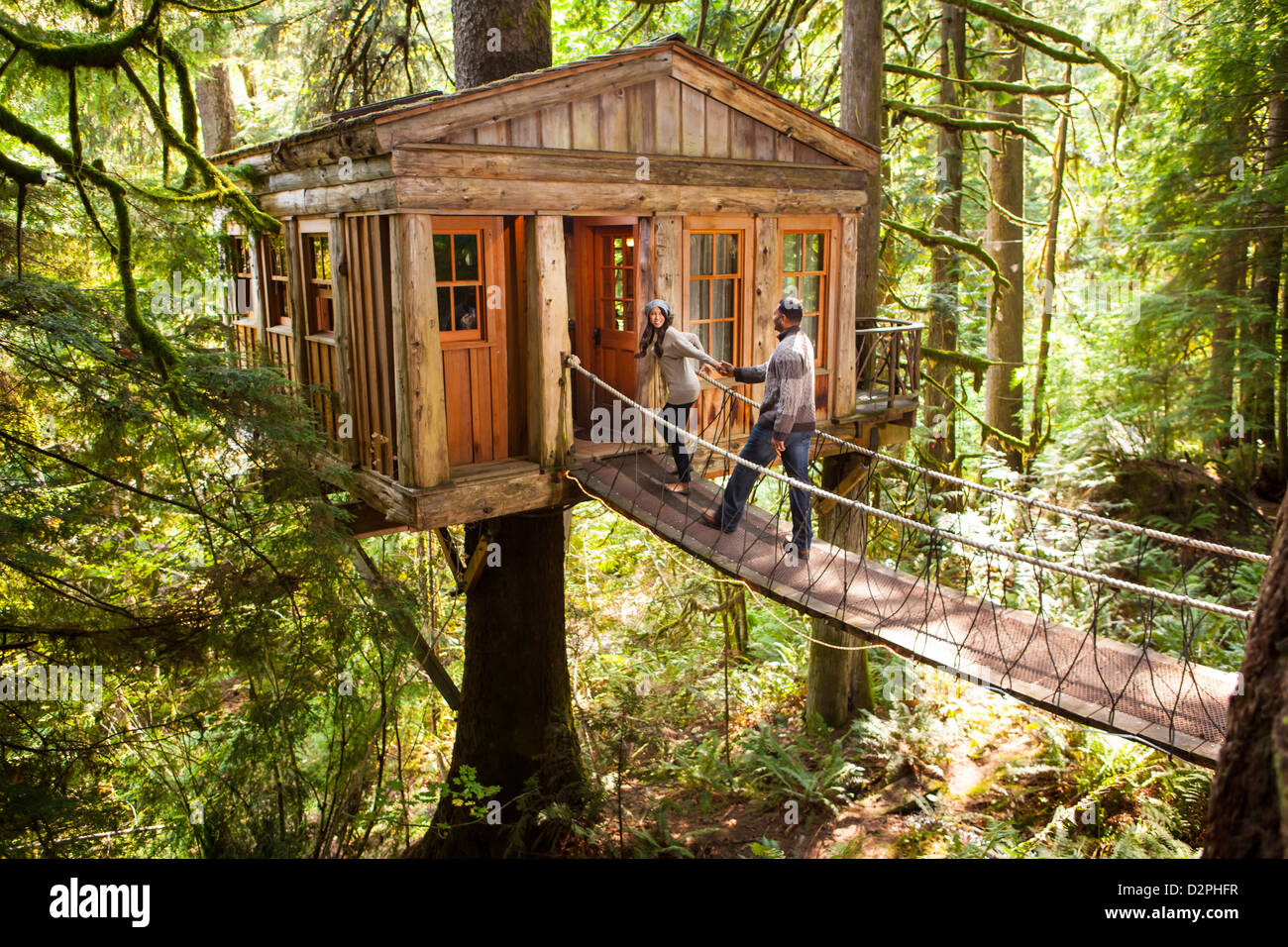 Couple on walkway of remote tree house Stock Photo - Alamy