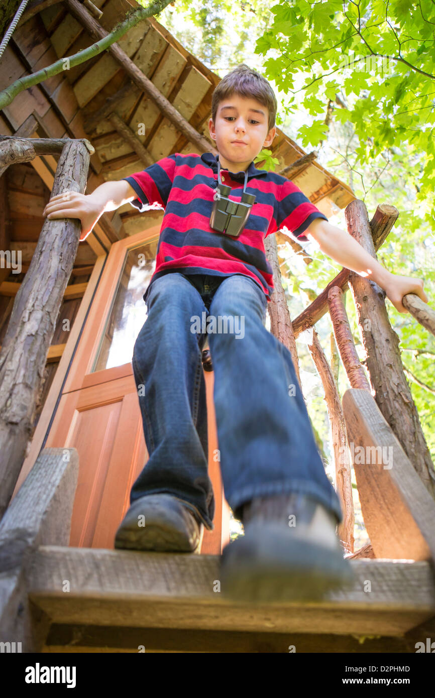 Caucasian boy climbing down from tree house Stock Photo - Alamy