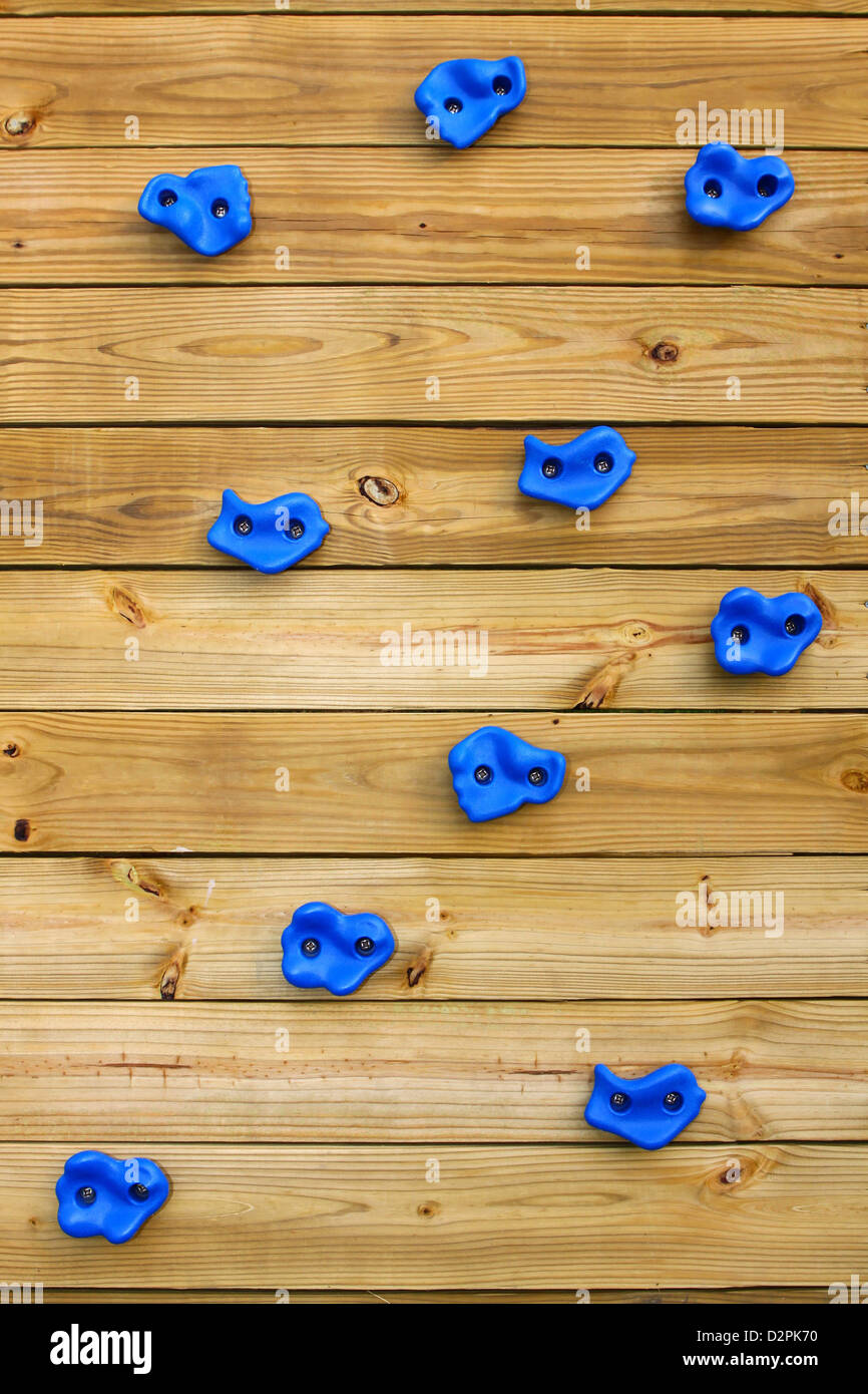 Climbing wall on a child's playground set. Blue pegs on treated wood ...