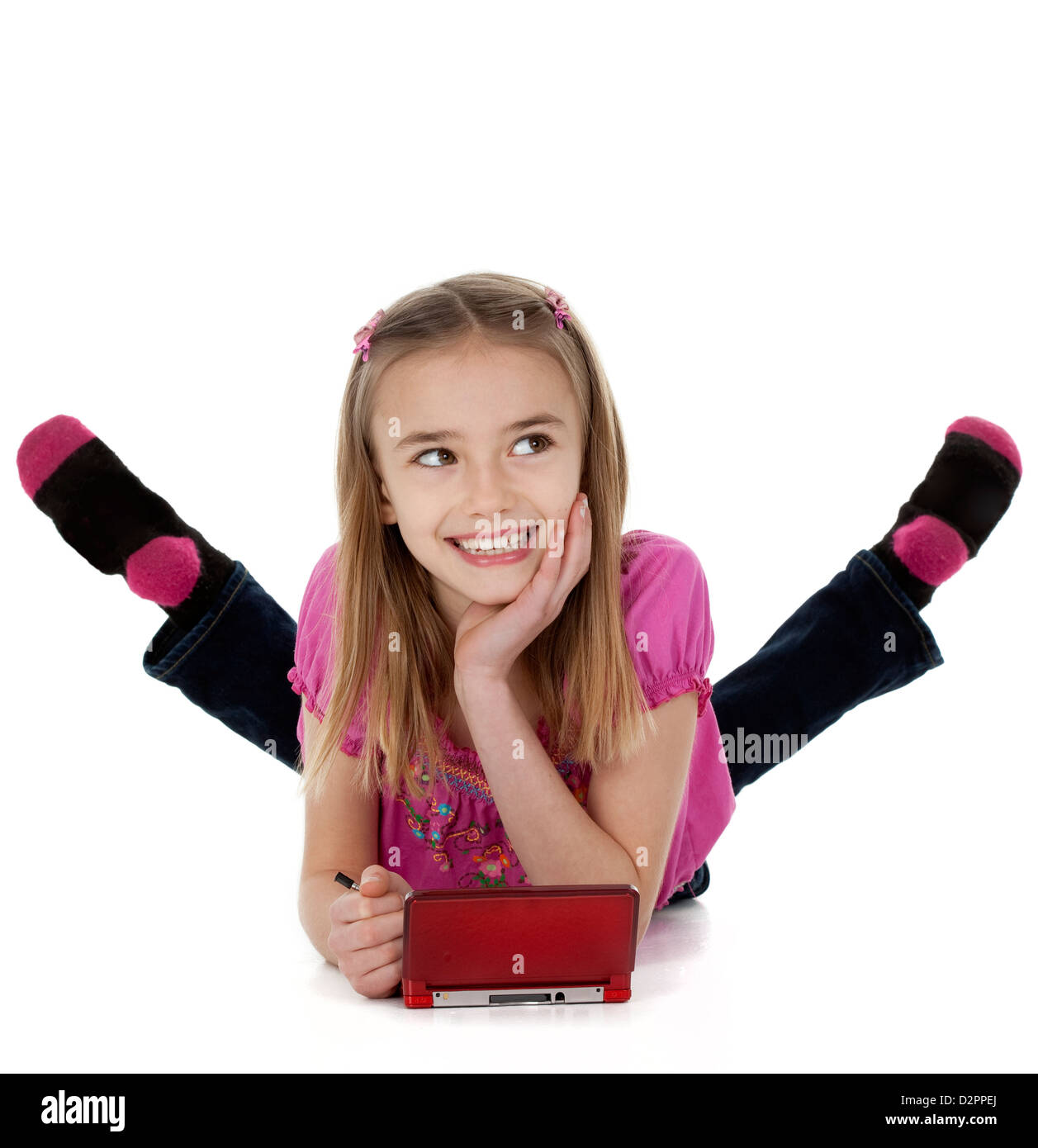 Cute female child lying on floor playing electronic game on white ...