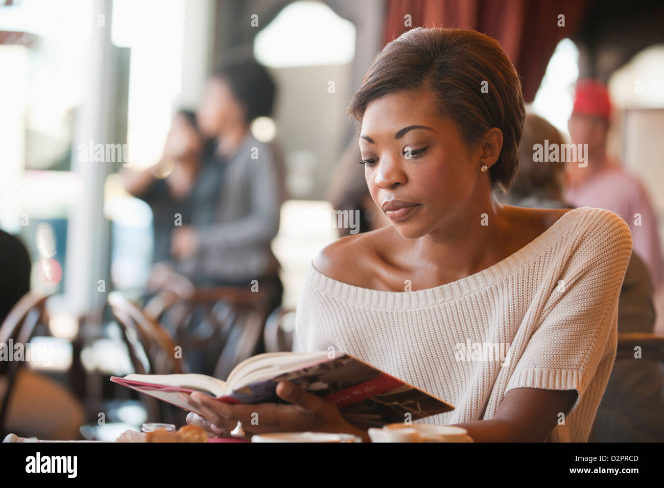 African American woman reading book in cafe Stock Photo - Alamy