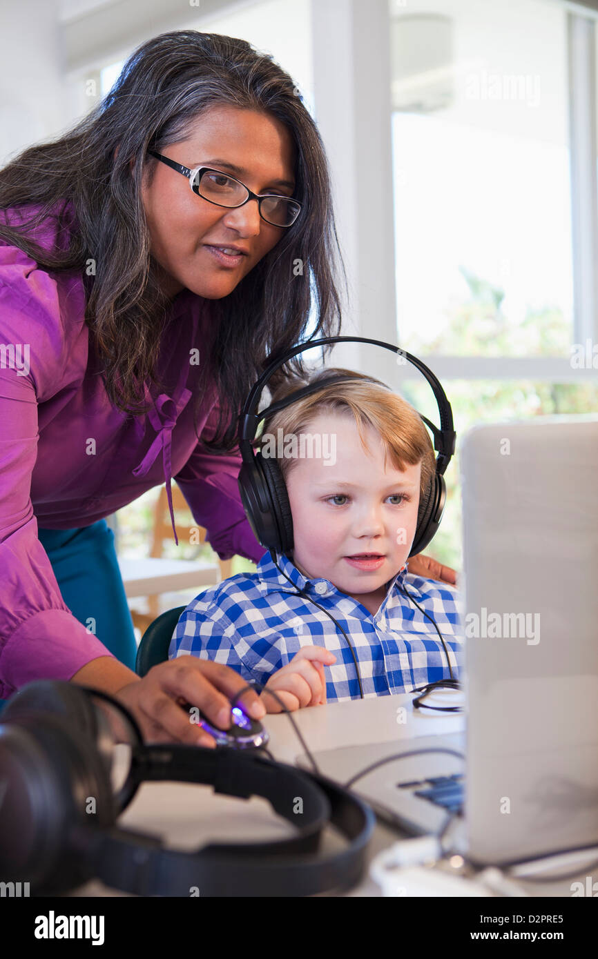 Teacher helping student using laptop in classroom Stock Photo - Alamy