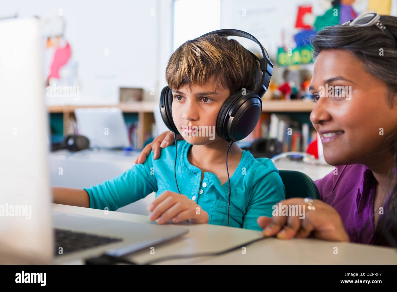 Teacher helping student using laptop Stock Photo - Alamy