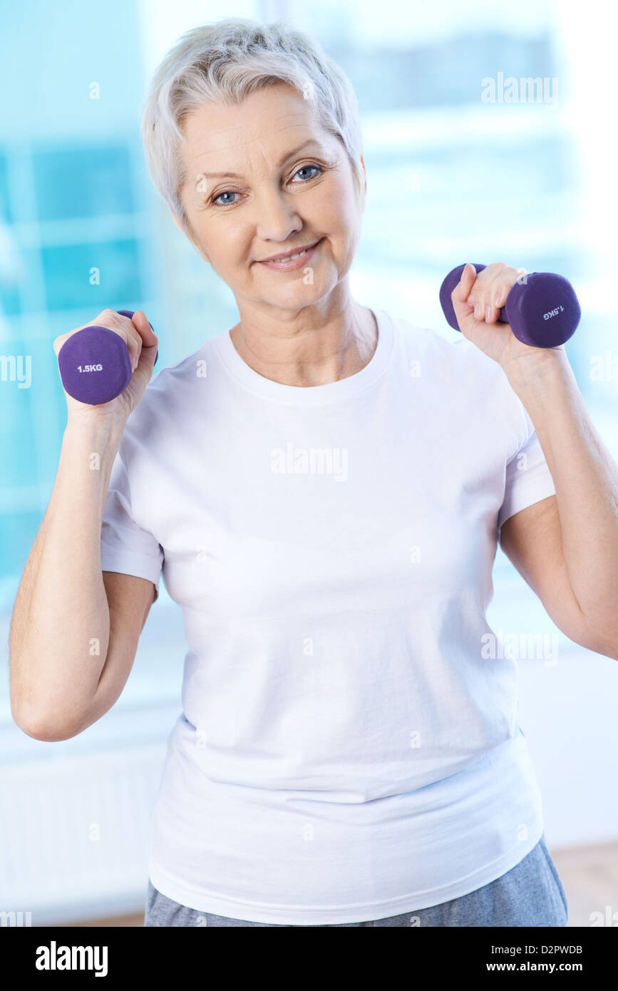 Portrait of pretty senior woman exercising with dumbbells Stock Photo ...