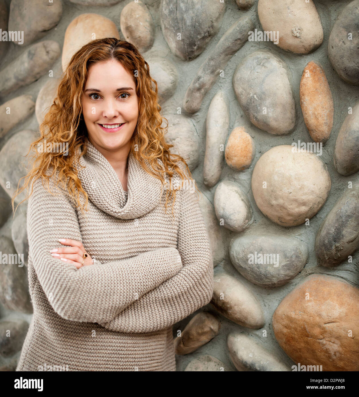 Smiling woman standing in front of stone wall Stock Photo - Alamy