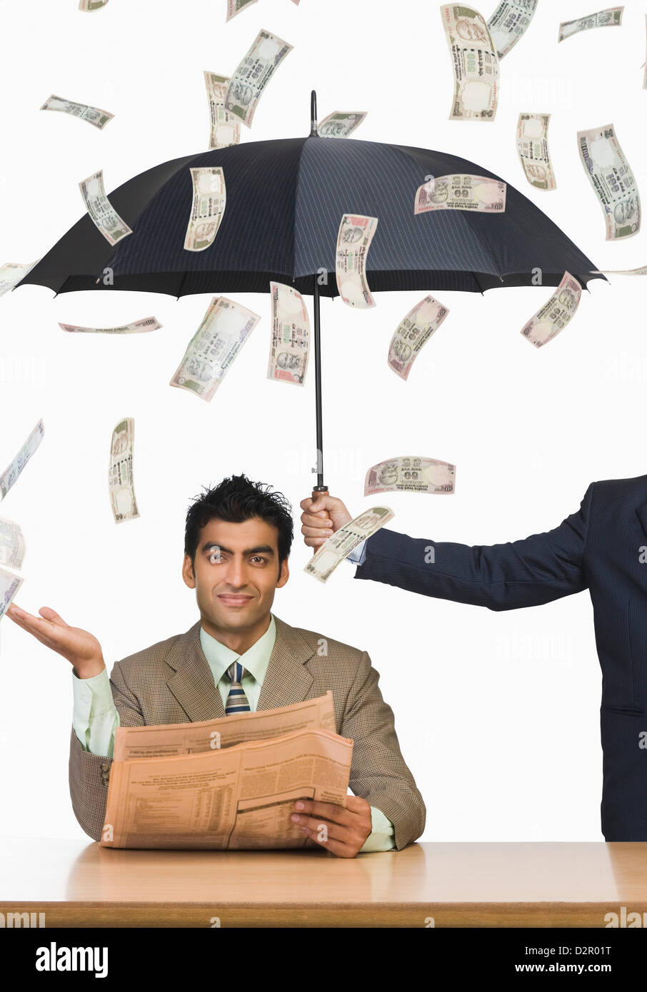 Money falling on businessman sitting under an umbrella Stock Photo - Alamy
