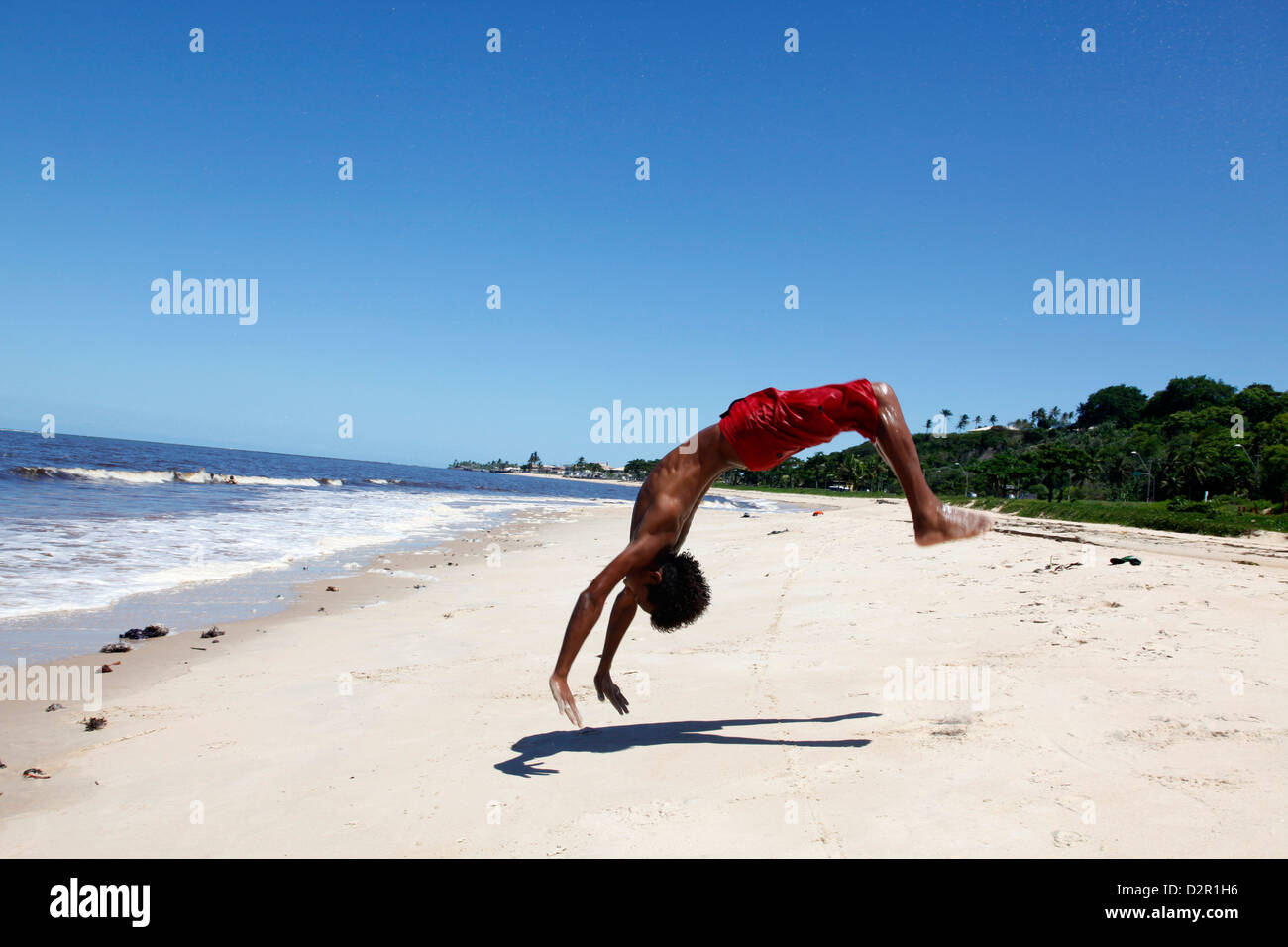 Young man doing acrobatics on Rio da Vila beach, Porto Seguro, Bahia ...