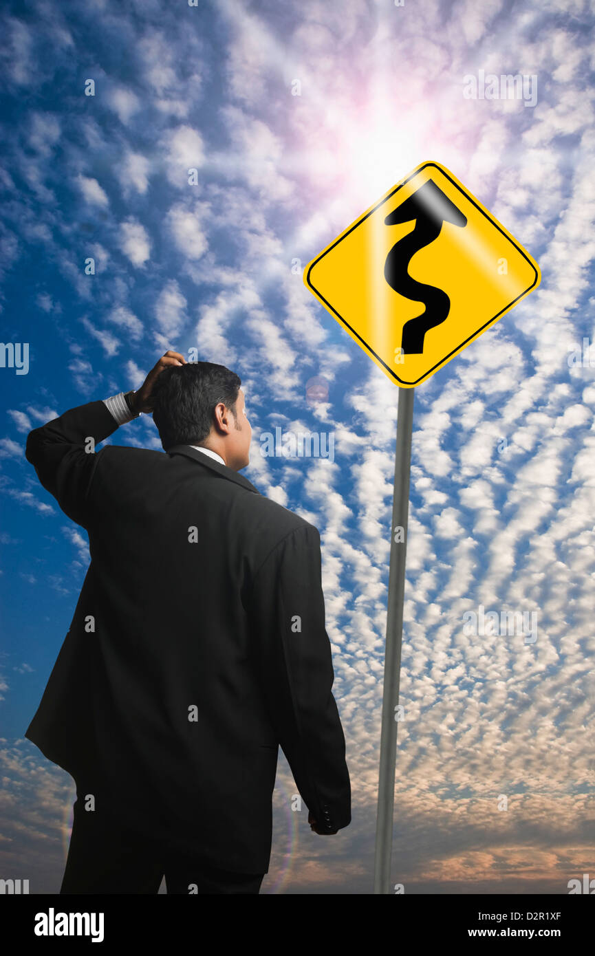 Businessman looking at a Zig Zag Road sign Stock Photo - Alamy