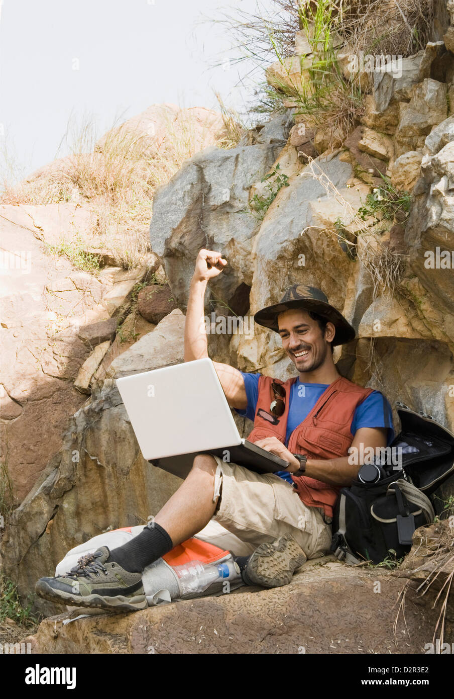 Hiker sitting on a rock and using a laptop Stock Photo - Alamy
