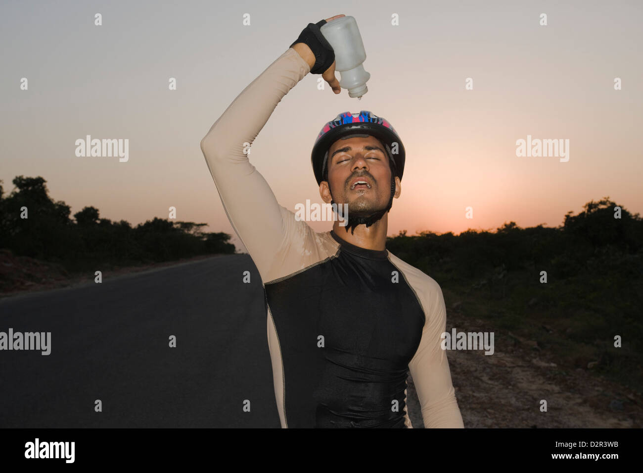 Cyclist pouring water over himself Stock Photo - Alamy