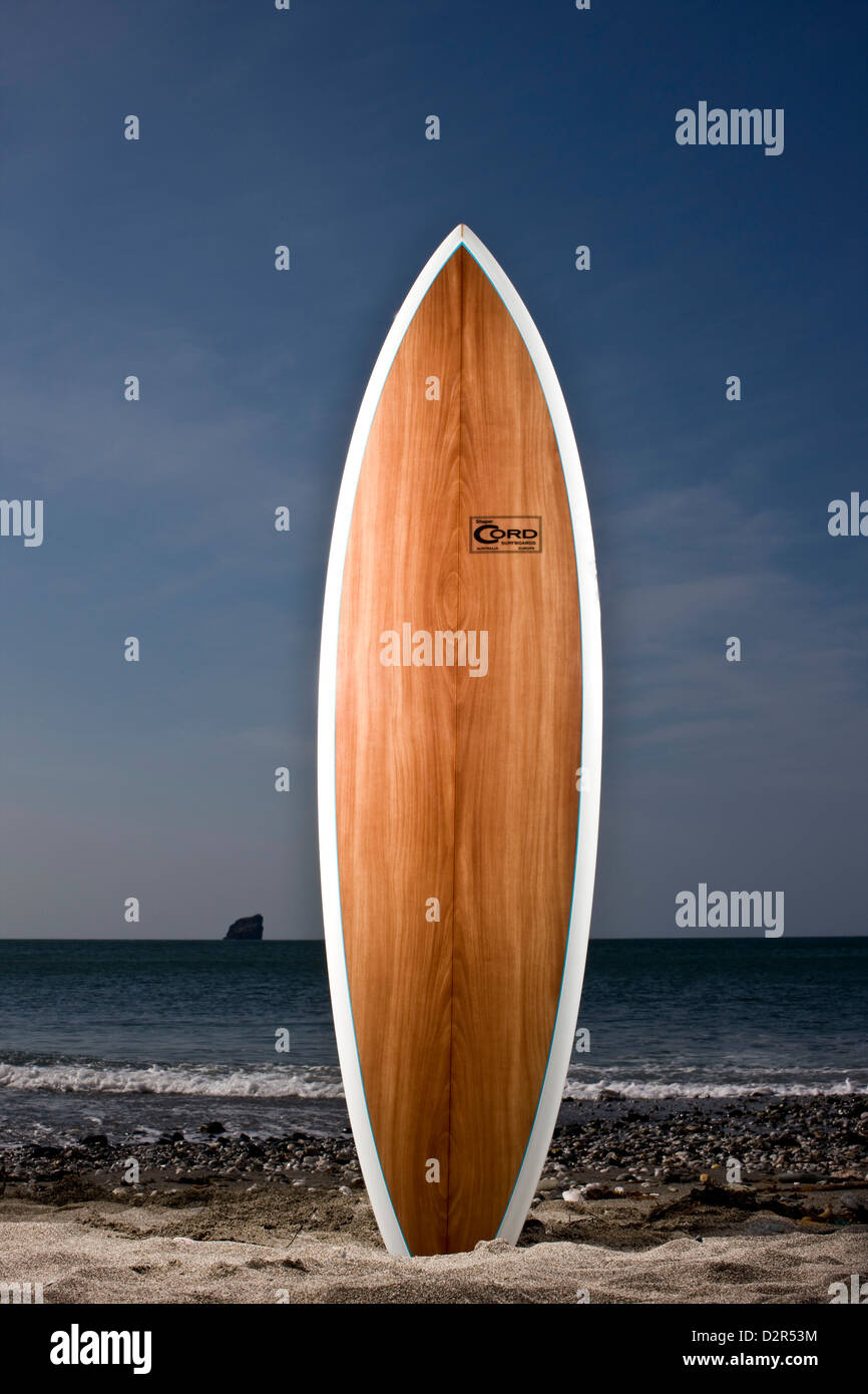 Smooth wooden surfboard standing on end at waters edge Stock Photo - Alamy