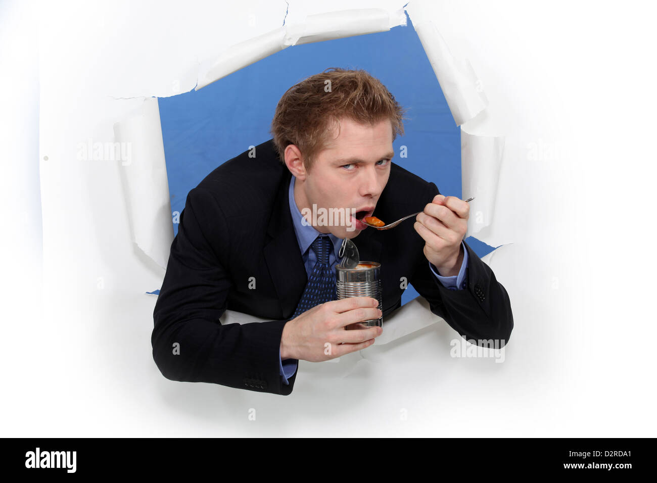 Businessman eating out of tin can Stock Photo - Alamy