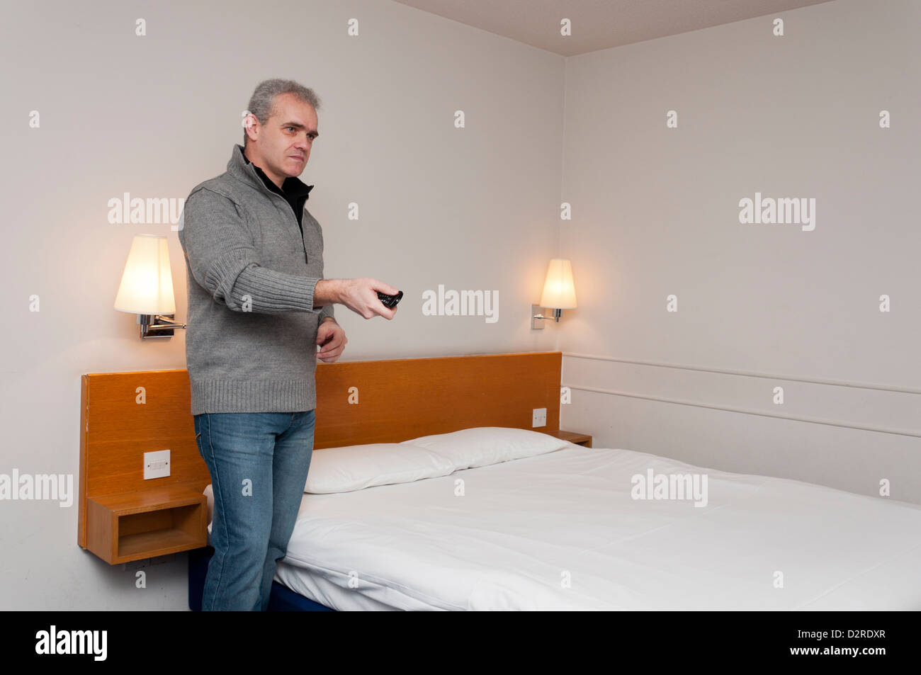 Man watching TV in hotel room, using remote control Stock Photo - Alamy