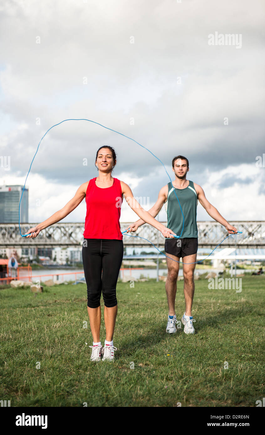 Young fitness couple exercising outdoor - jumping with skipping rope ...