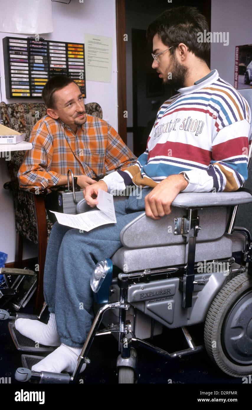 Helper in disabled center chatting with young man in wheelchair Stock ...