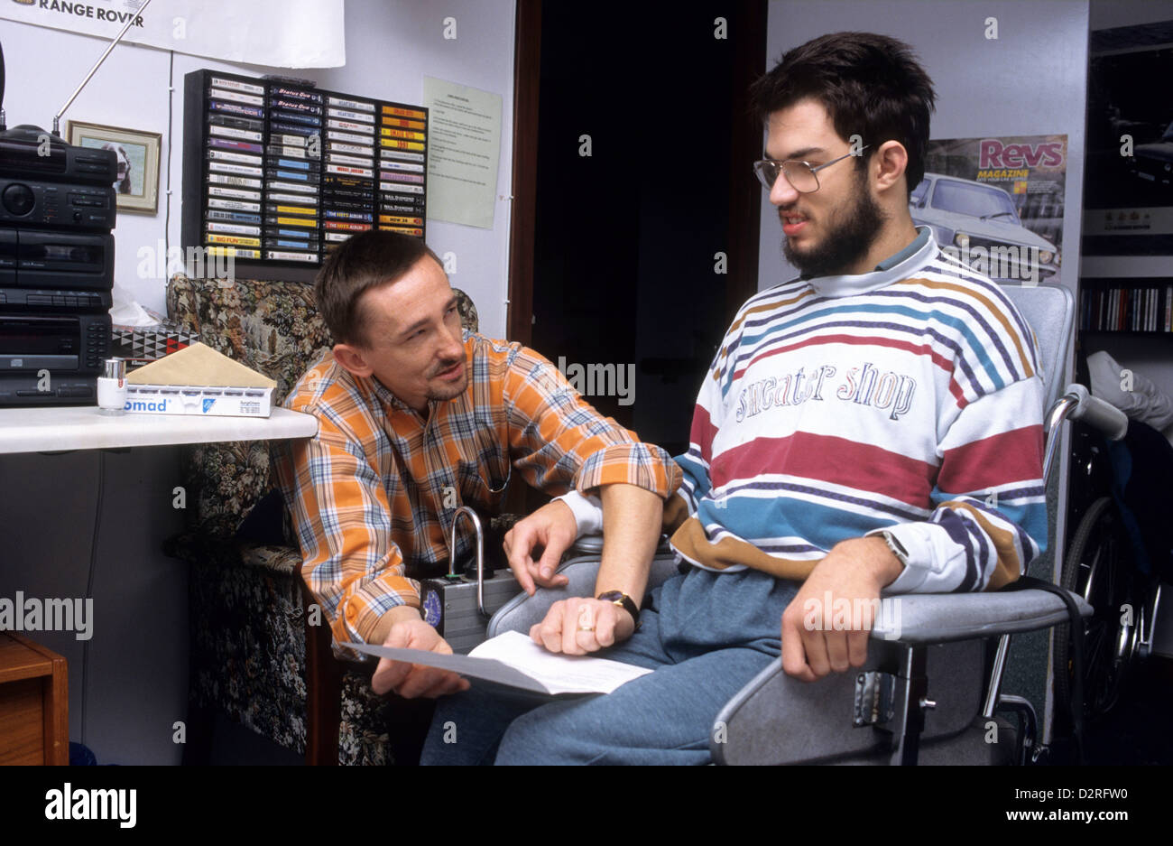 Helper in disabled center chatting with young man in wheelchair Stock ...