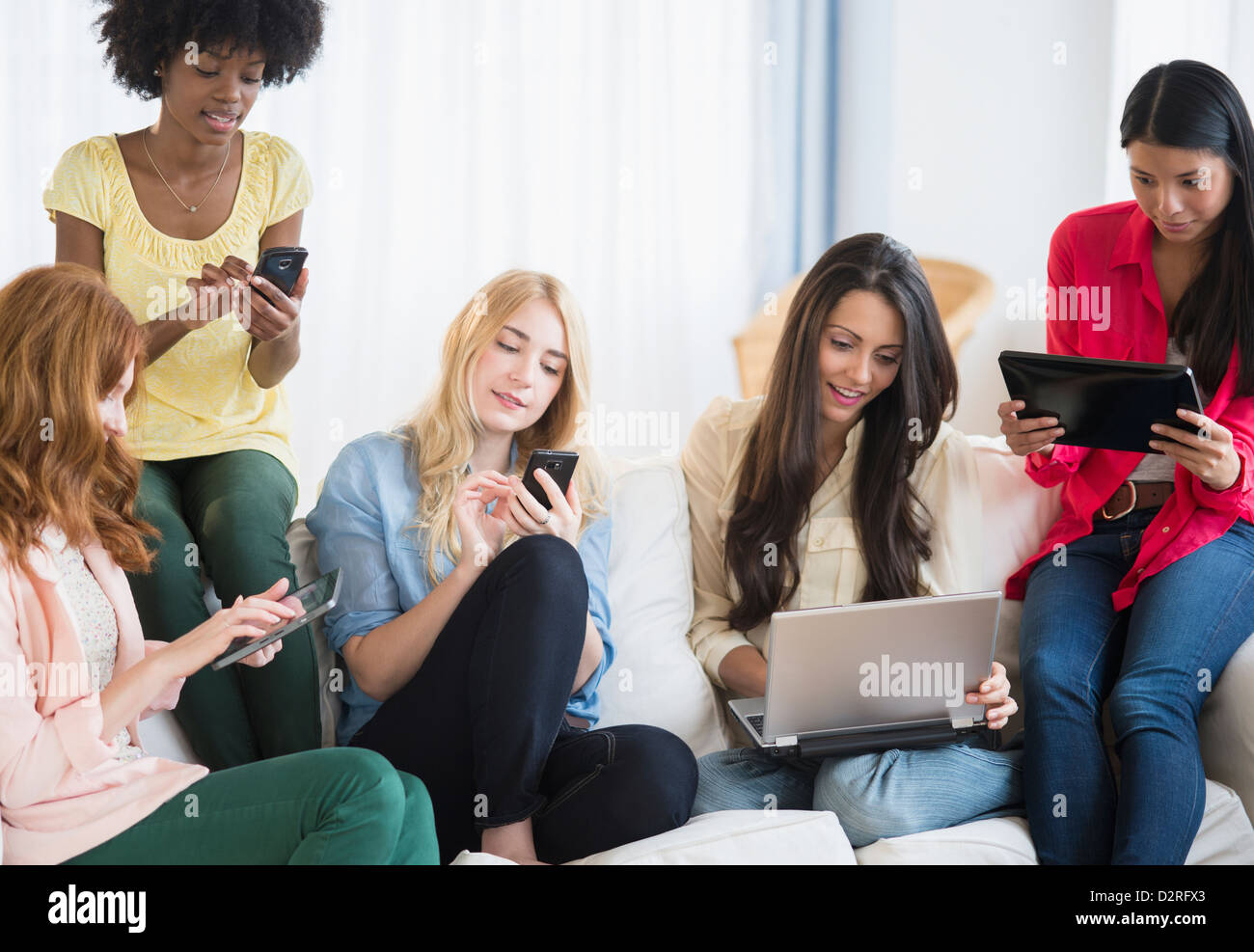 Women using technology on sofa Stock Photo - Alamy