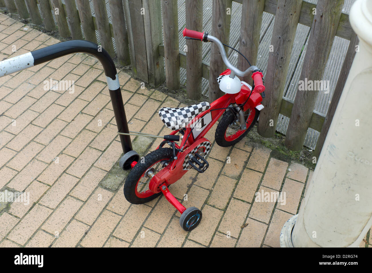 Child's red bike chained to post Stock Photo - Alamy