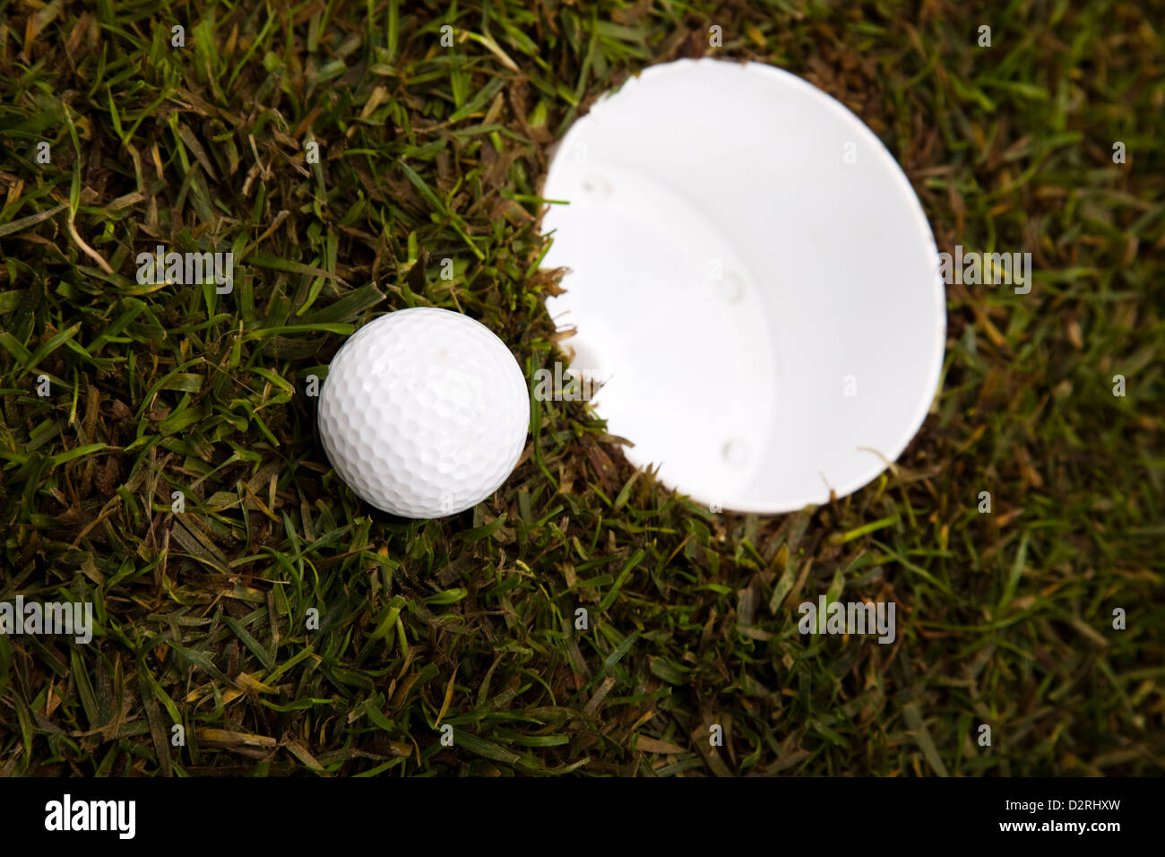 Golf ball on lip of cup Stock Photo - Alamy
