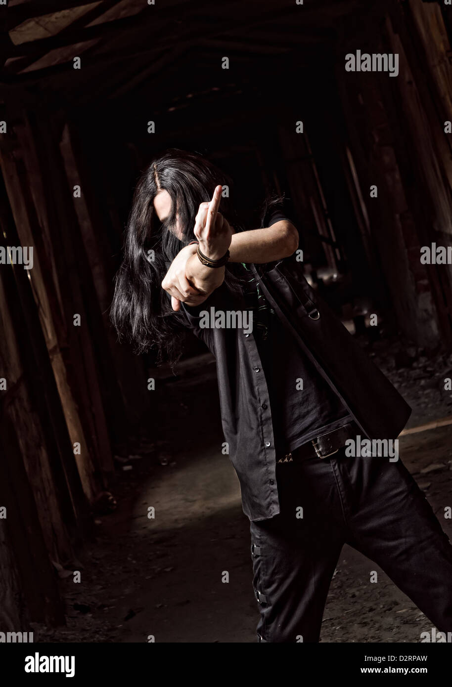 Portrait of long-haired young man making offensive gesture (middle ...