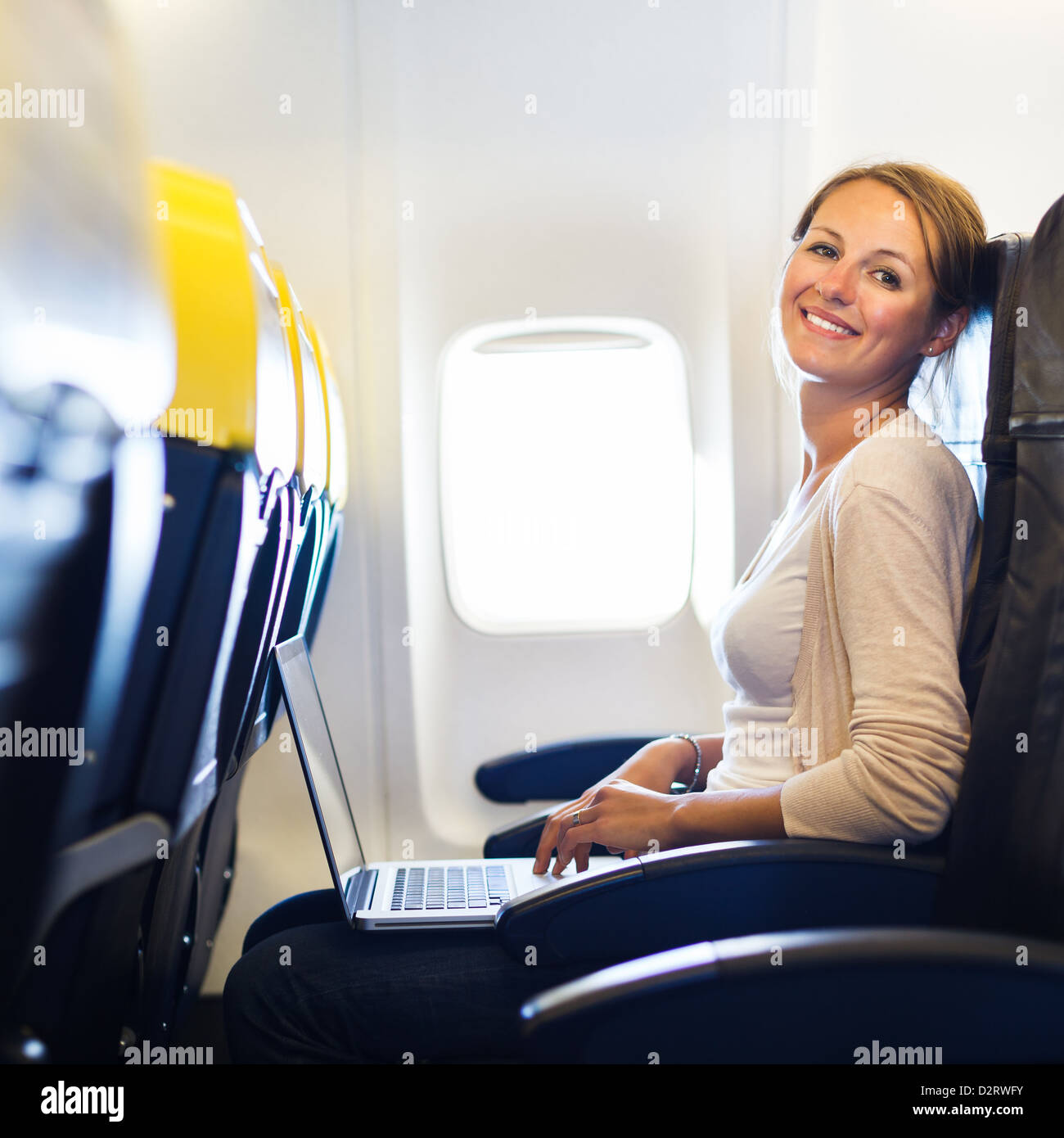 Young woman working on her laptop computer on board of an airplane ...