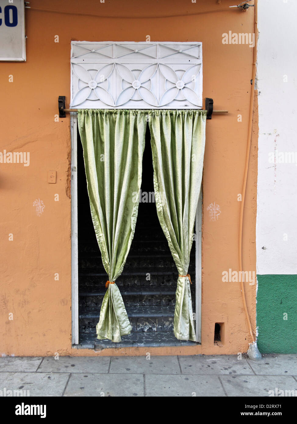 curtained doorway in ochre painted plaster street wall with pale green ...