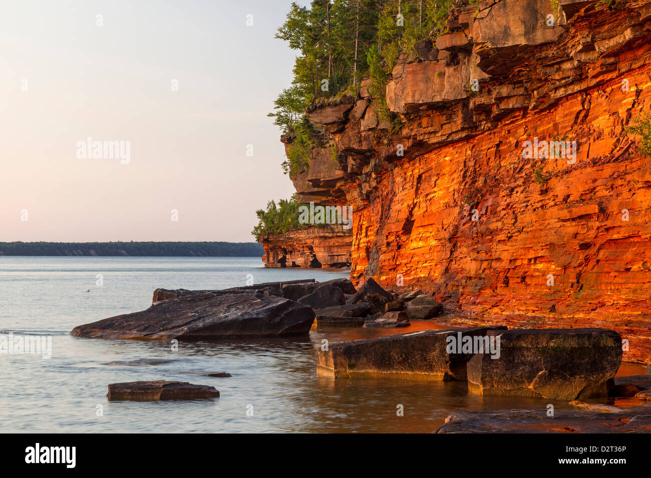 Layered sandstone cliffs and sea caves at sunrise on Devils Island in ...