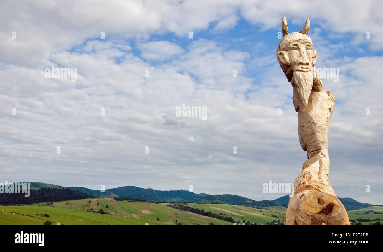 Wooden devil, sculpture on the sky, empty landscape, cloud, rural ...