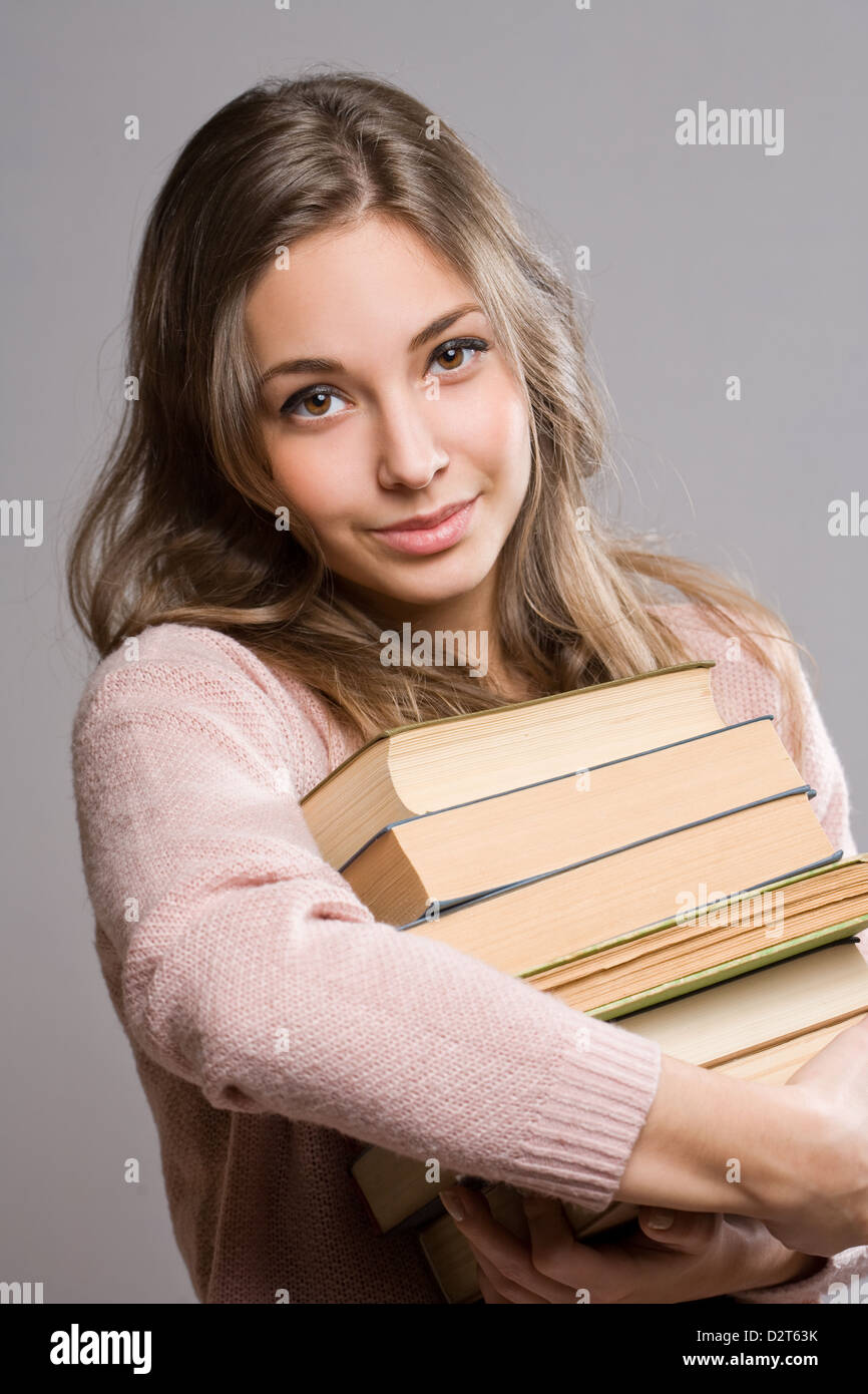 Portrait of tired looking young student with large pile of books Stock ...