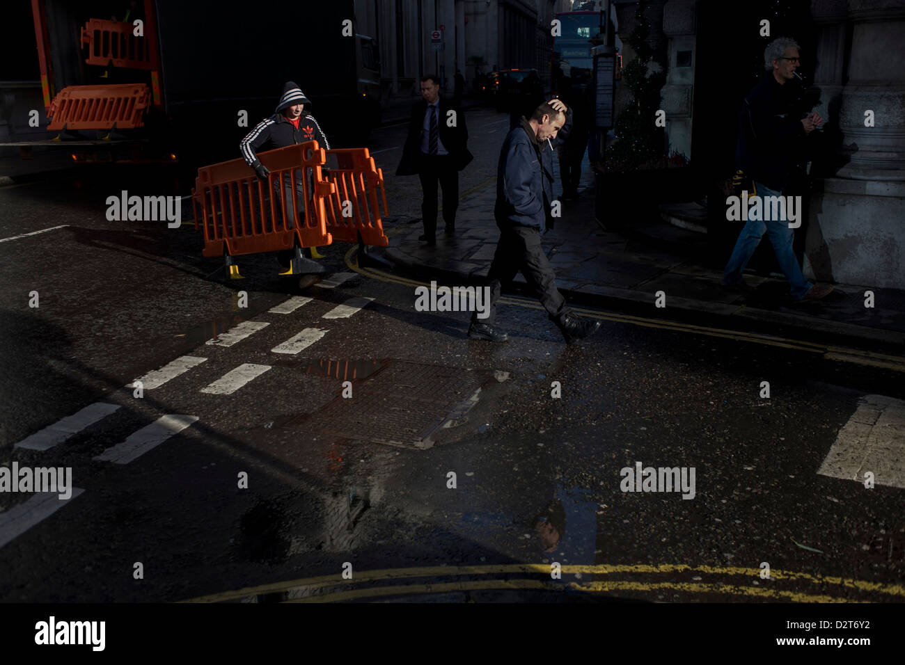 In strong sunlight, a workman delivers construction site fencing in the ...