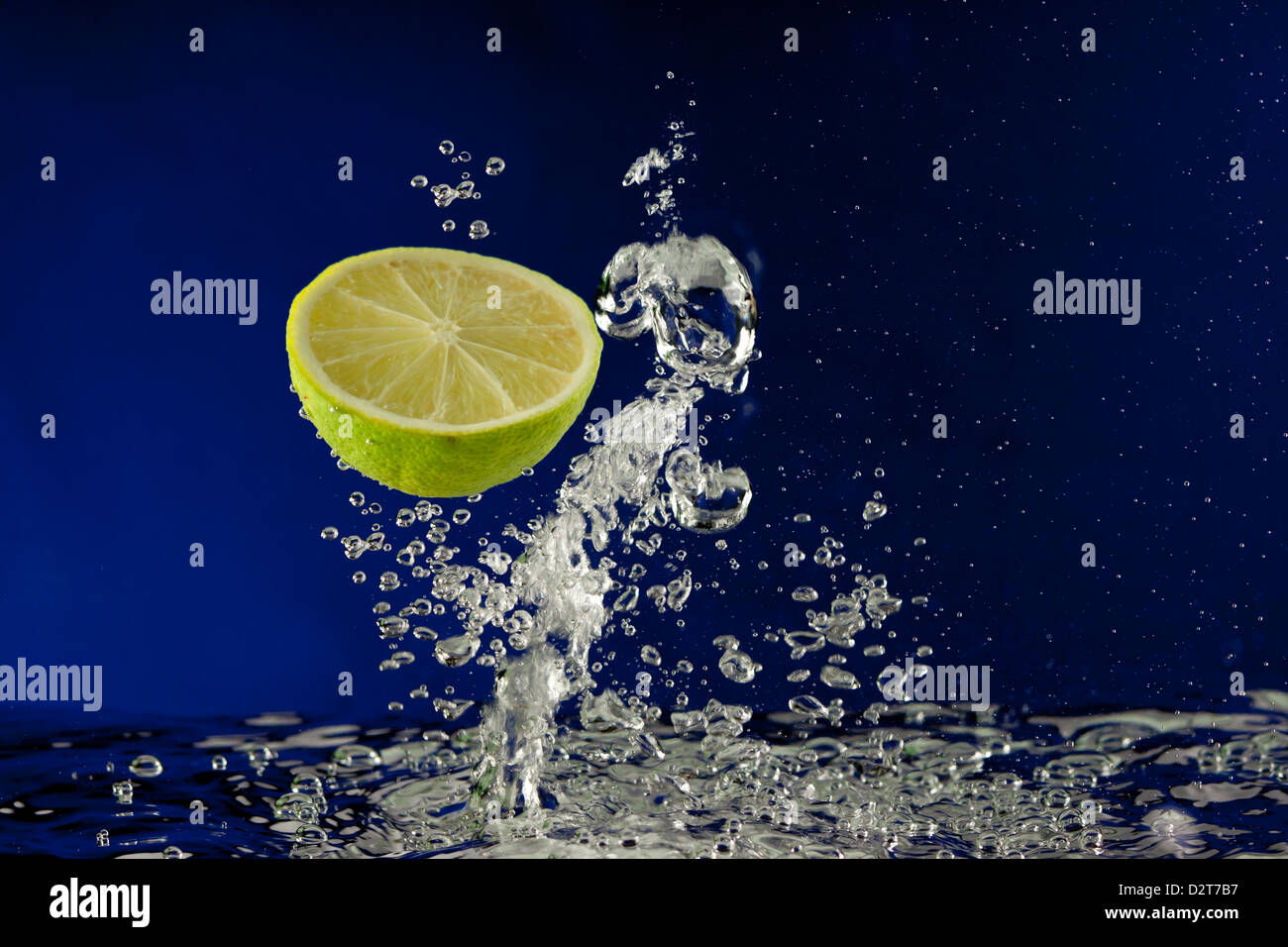 Fruit lime splash in water with bubbles against blue background Stock ...