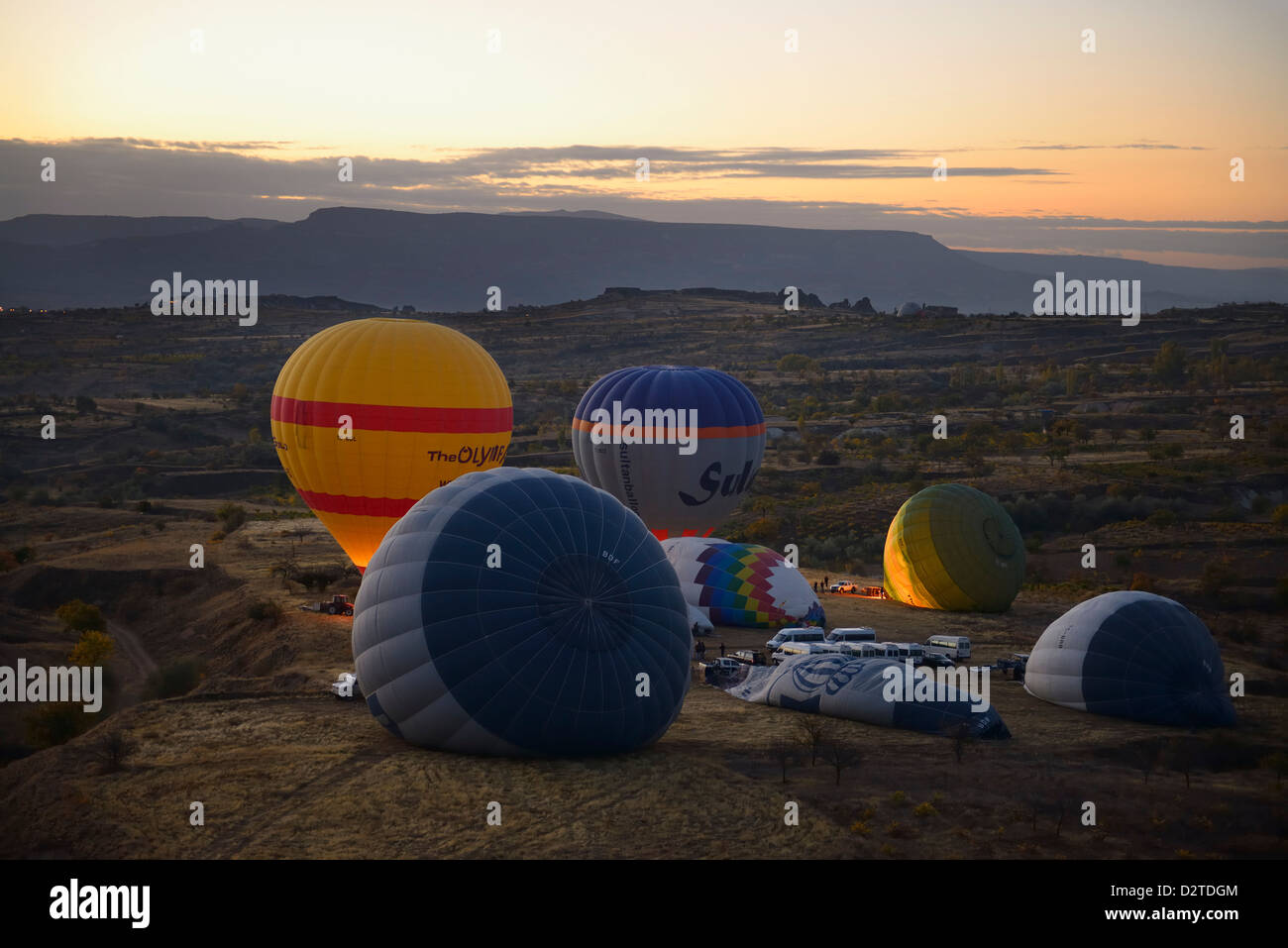 Hot air balloons being inflated and taking off at dawn in Cappadocia ...
