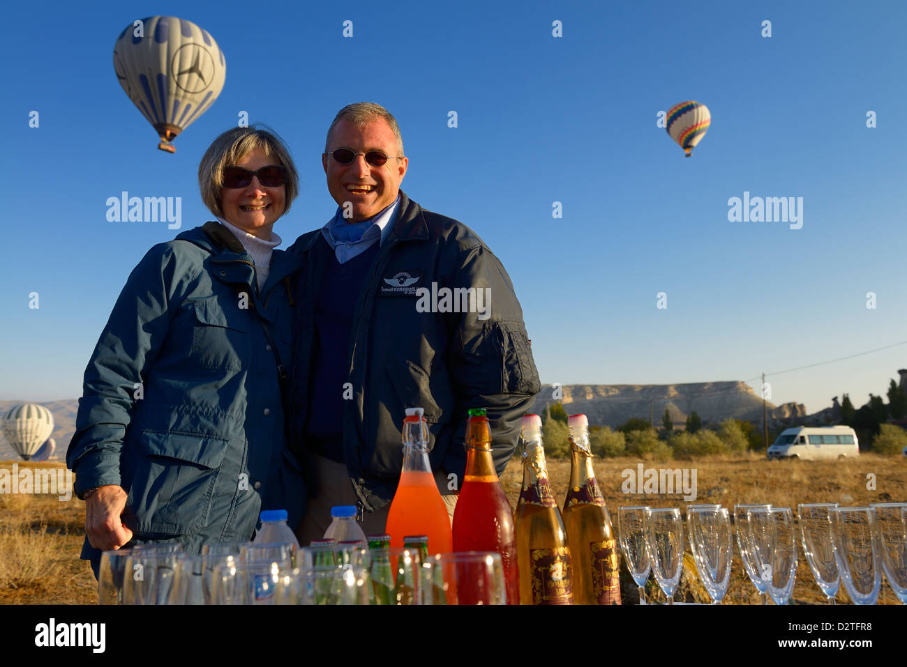 Hot air balloon pilot celebrating with female tourist toasting a ...